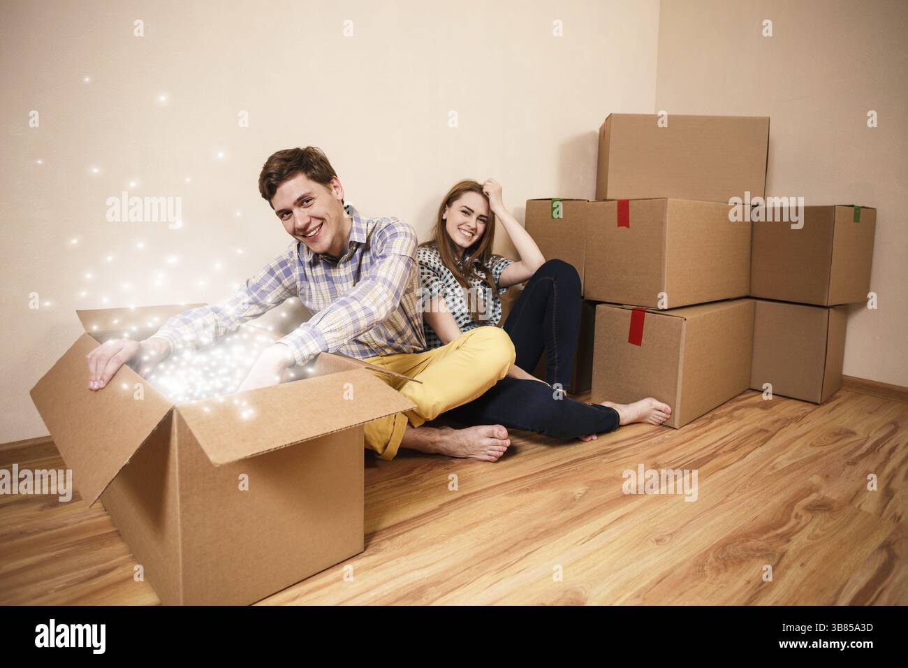 Young couple unpacking boxes in a living room Stock Photo - Alamy