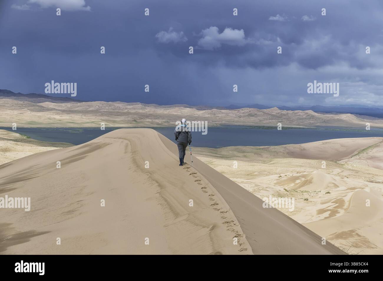 Tourist walking along the edge of the sand dune. Large barkhan in ...