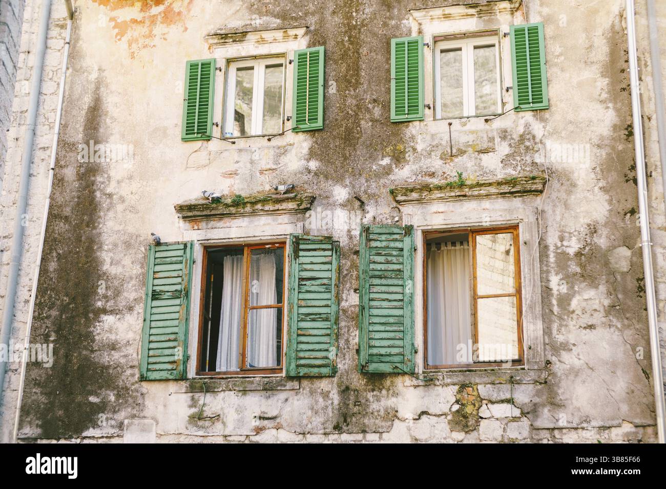 An old multi-storey building with windows and wooden shutters with ...