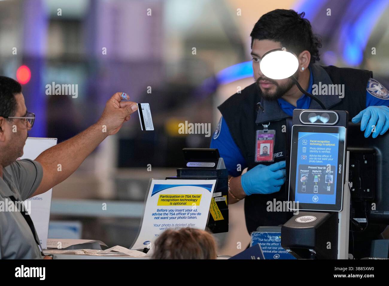 A TSA employee checks documents as people move through security at ...