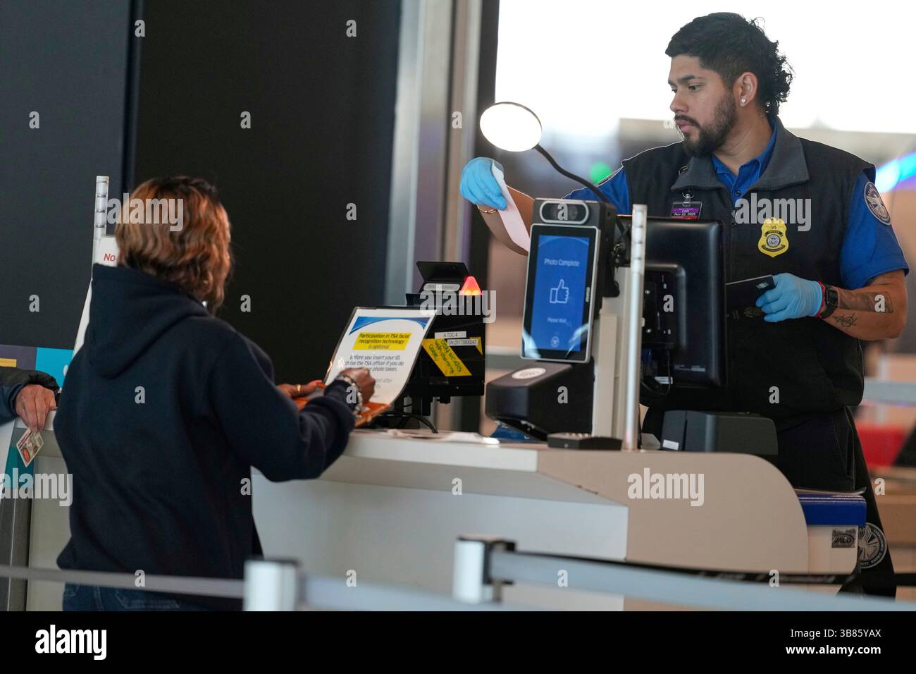 A TSA employee checks documents as people move through security at ...