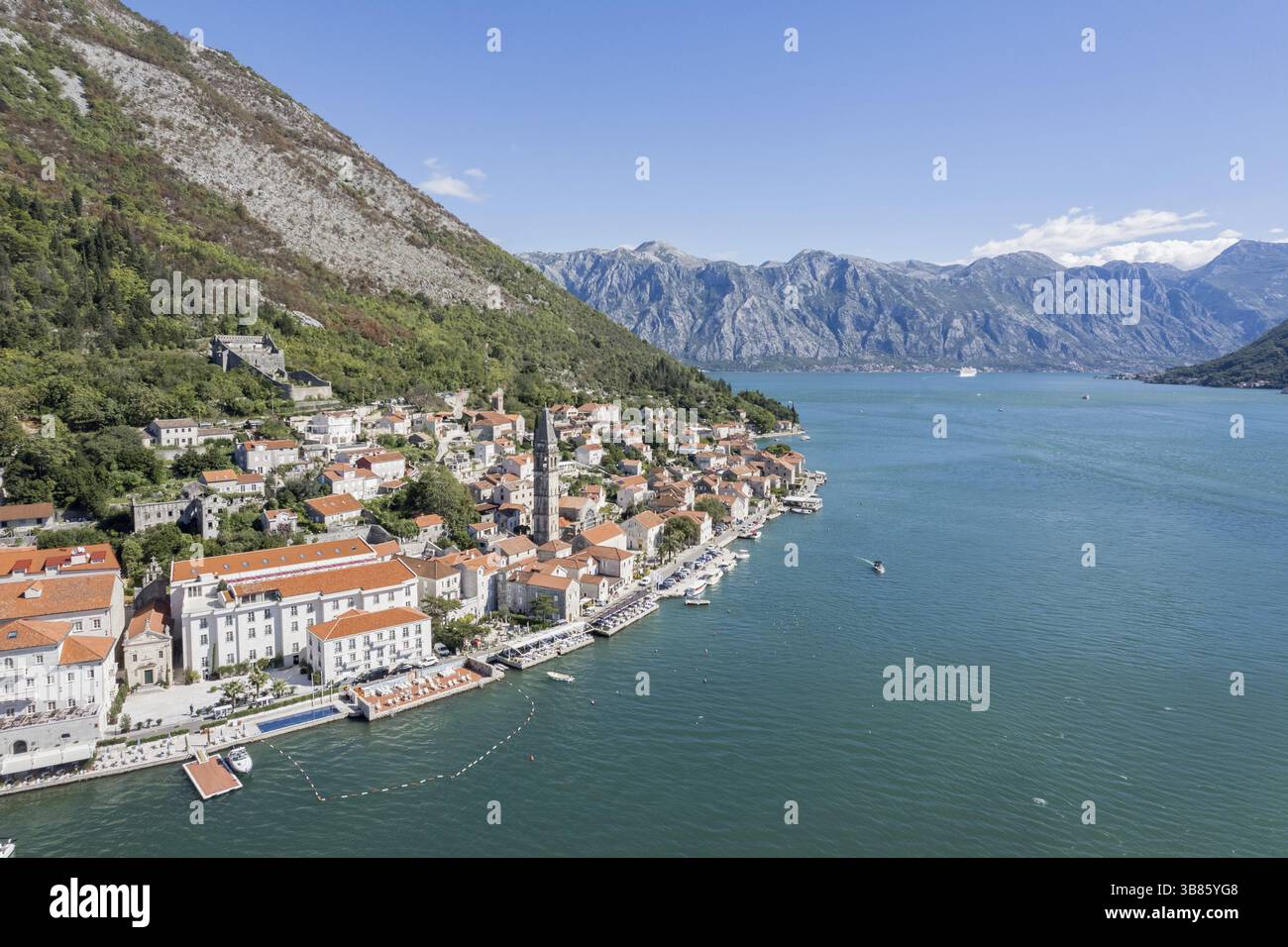Yacht sails along the coast of Perast with ancient houses and the bell ...