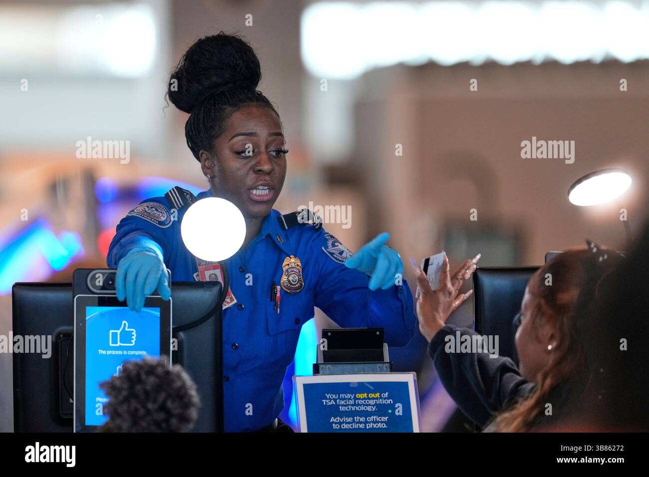 A TSA employee checks IDs as people move through security at Newark ...