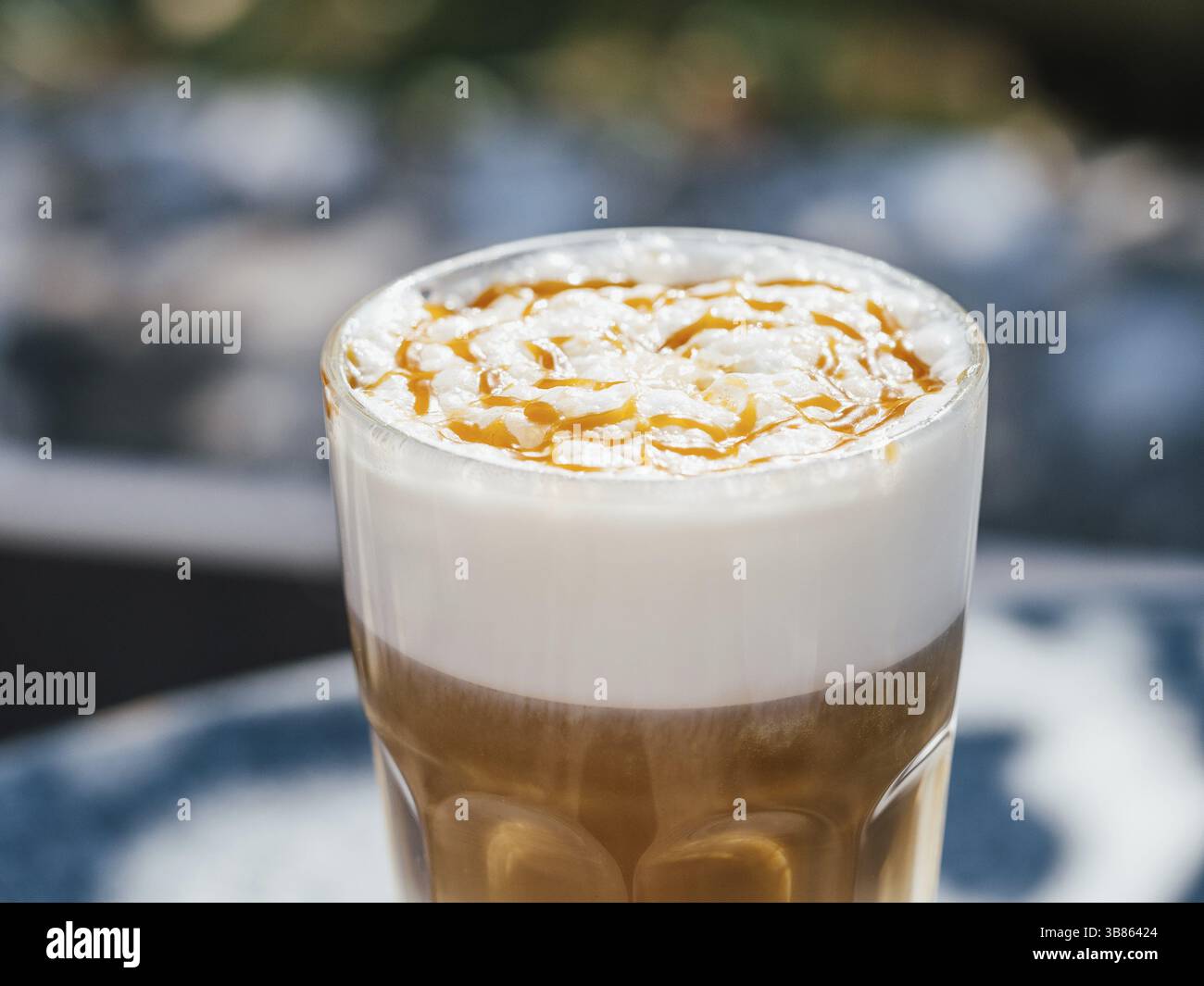 Hot latte macchiato coffee with caramel on tabletop outdoors. Natural ...