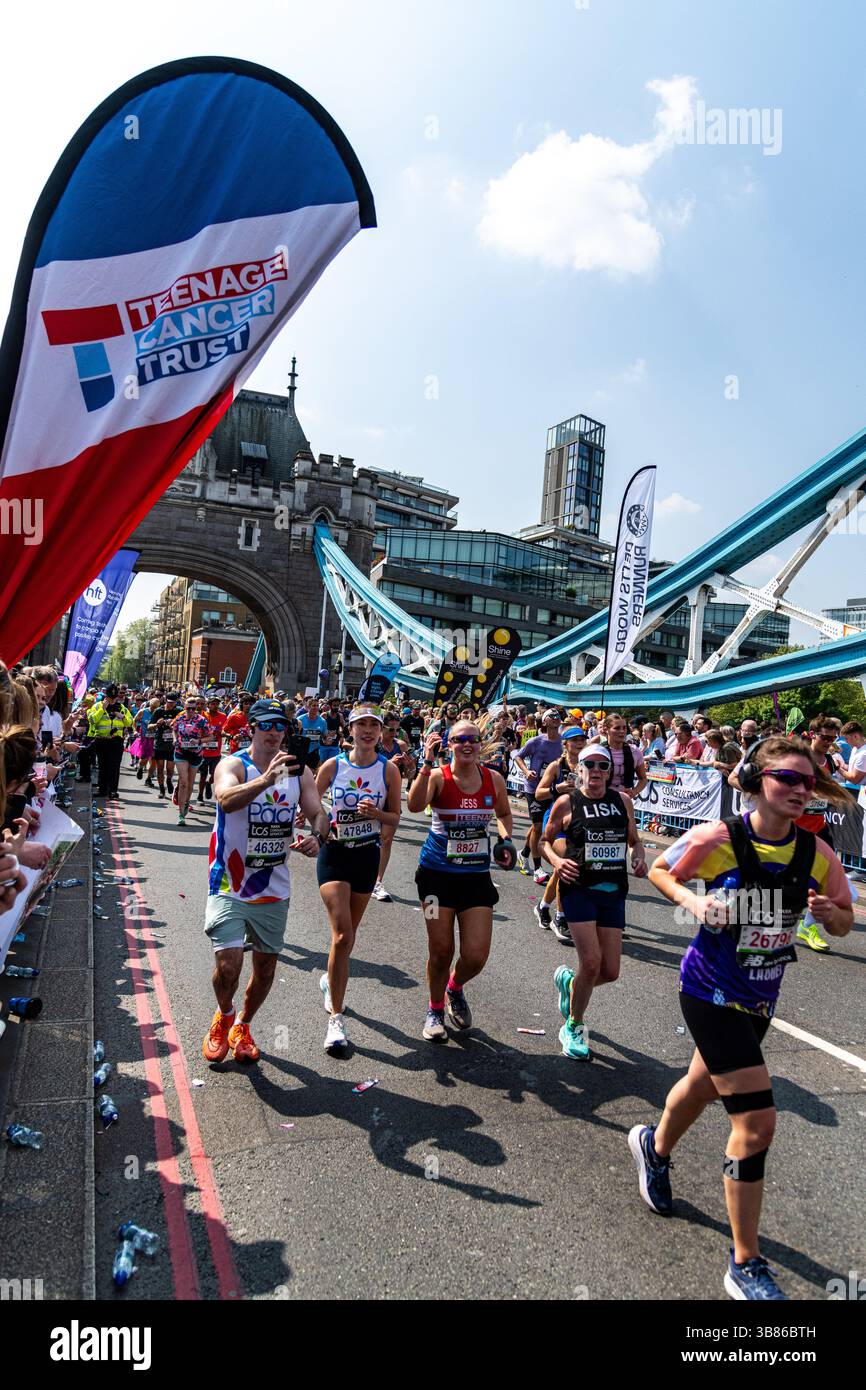 Runners running at the London Marathon 2025 for Teenage Cancer Trust charity on Tower Bridge in ...