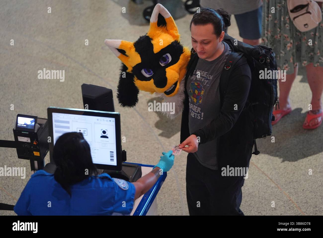 A traveler hands a TSA agent their ID while passing through security at ...