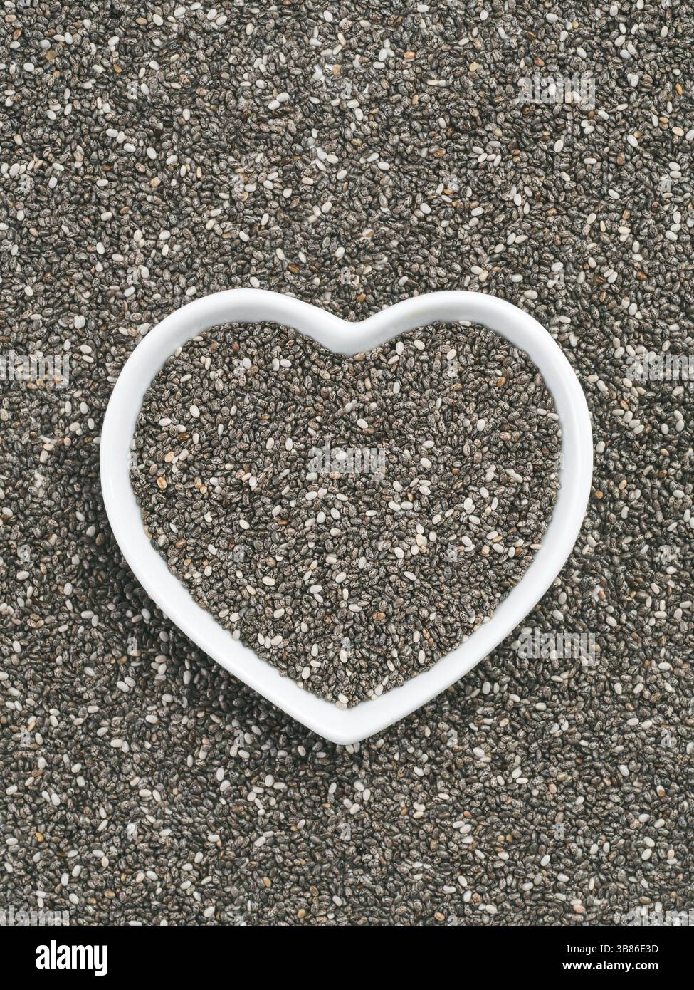 Heart-shaped bowl of chia seeds on chia background. Gluten free and ...