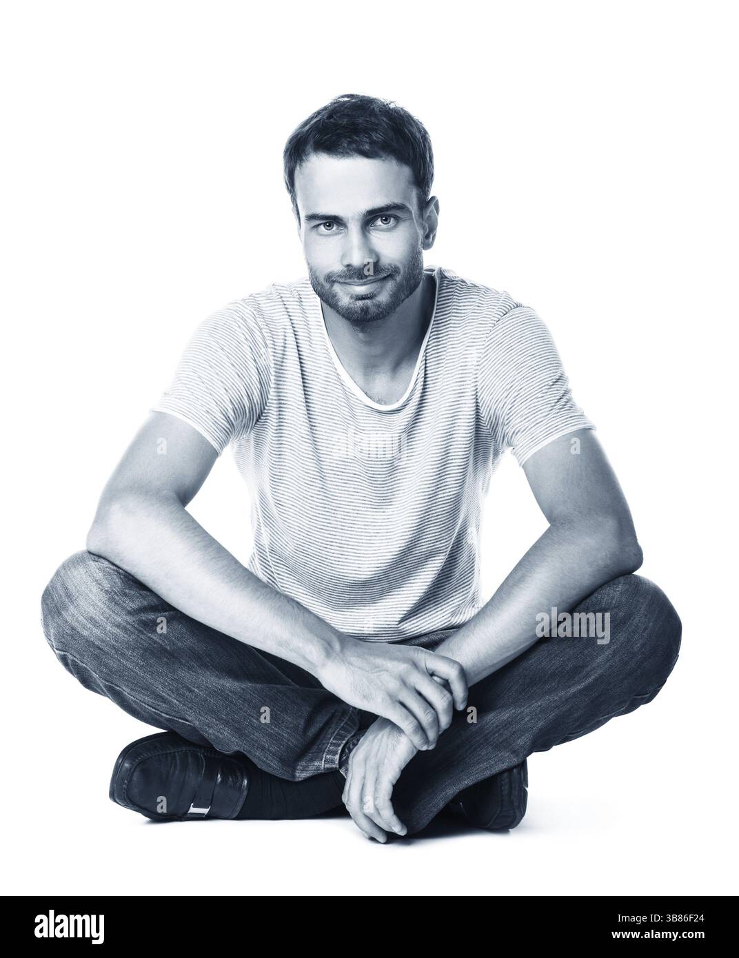 Casual young man sitting on the floor with his legs crossed isolated on ...