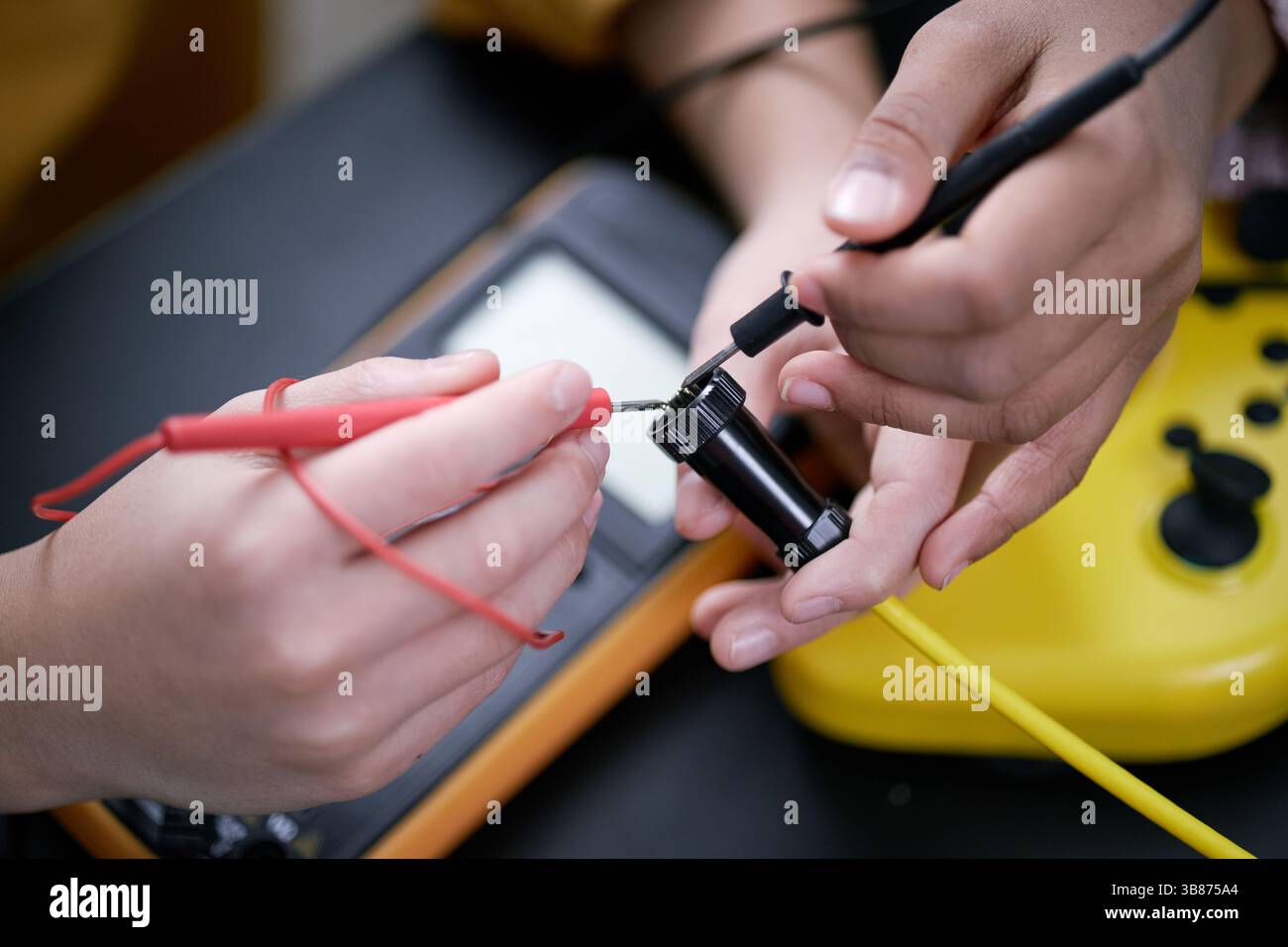 Close-up of hands connecting electrical components using multimeter ...