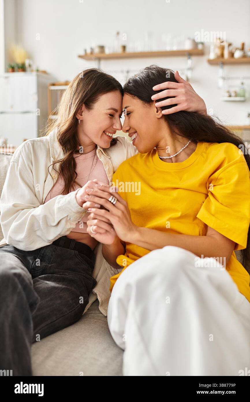 Two women share a tender moment at home, exchanging smiles and holding ...