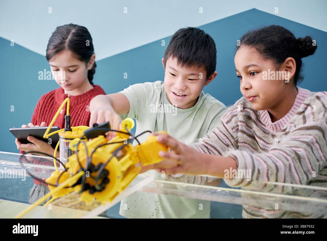 Three children focusing on building and programming robots with ...