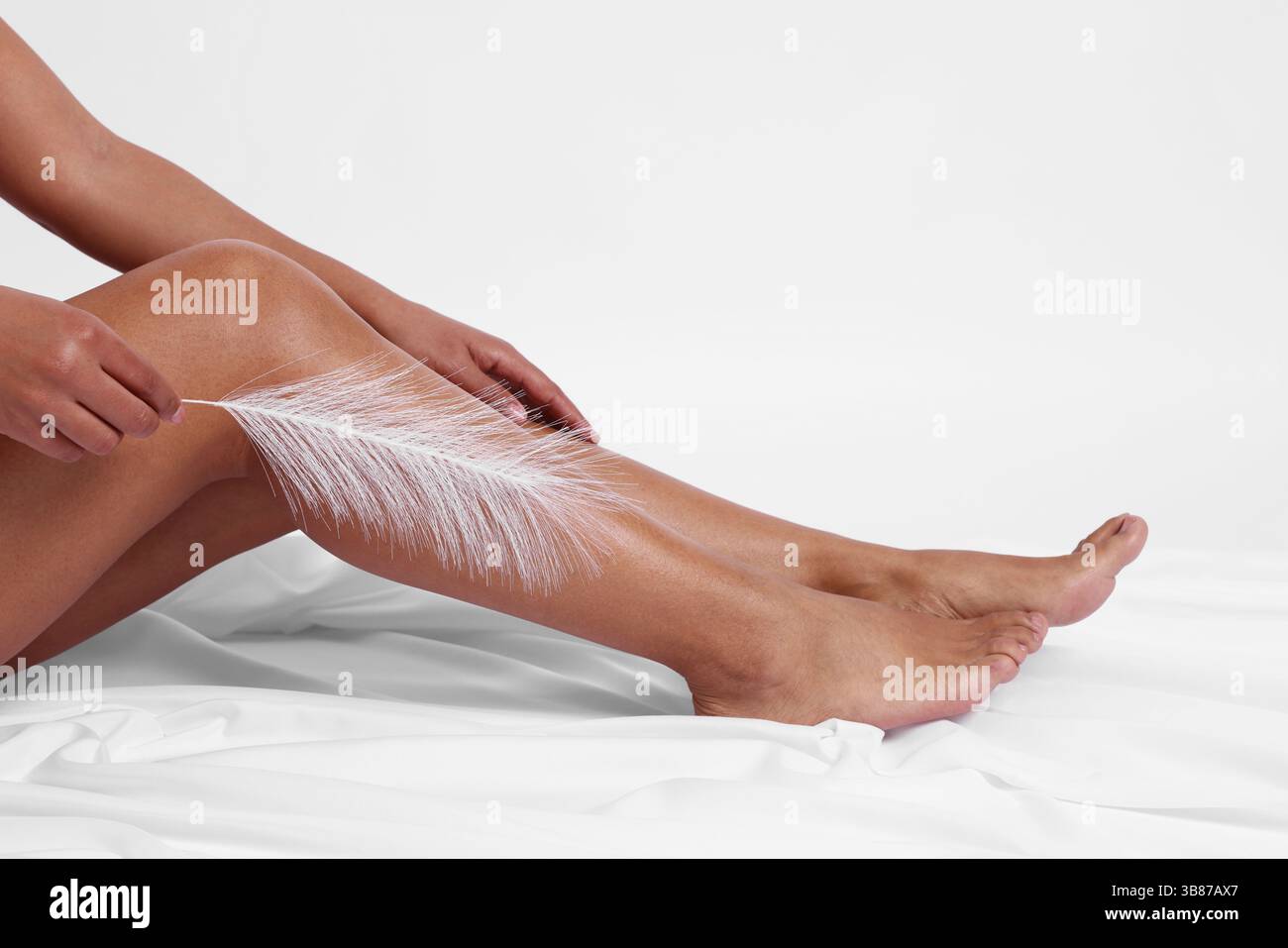 Epilation. Woman with feather showing her legs with smooth soft skin on ...