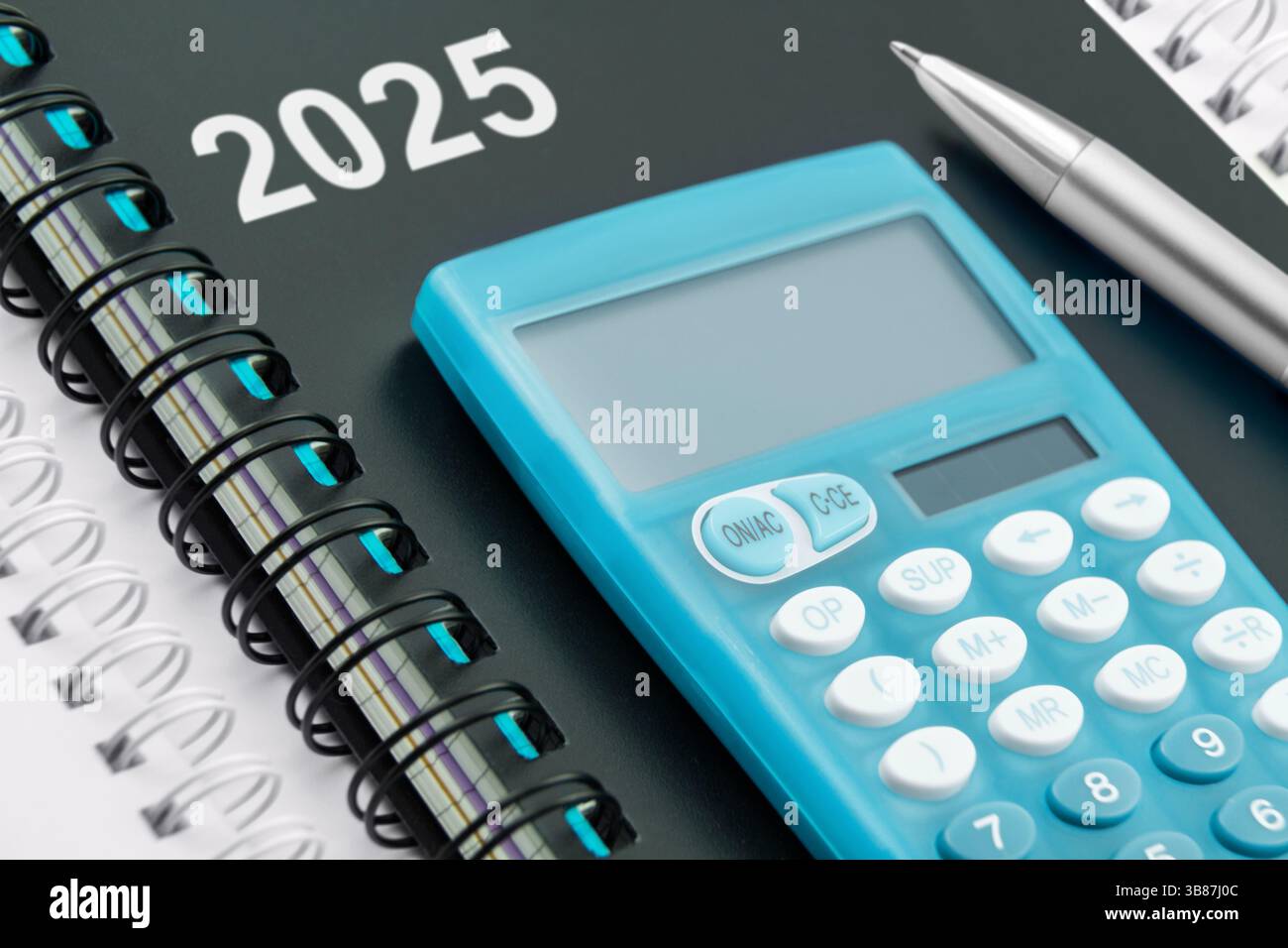 Blue calculator and calendar 2025 with pen Stock Photo - Alamy