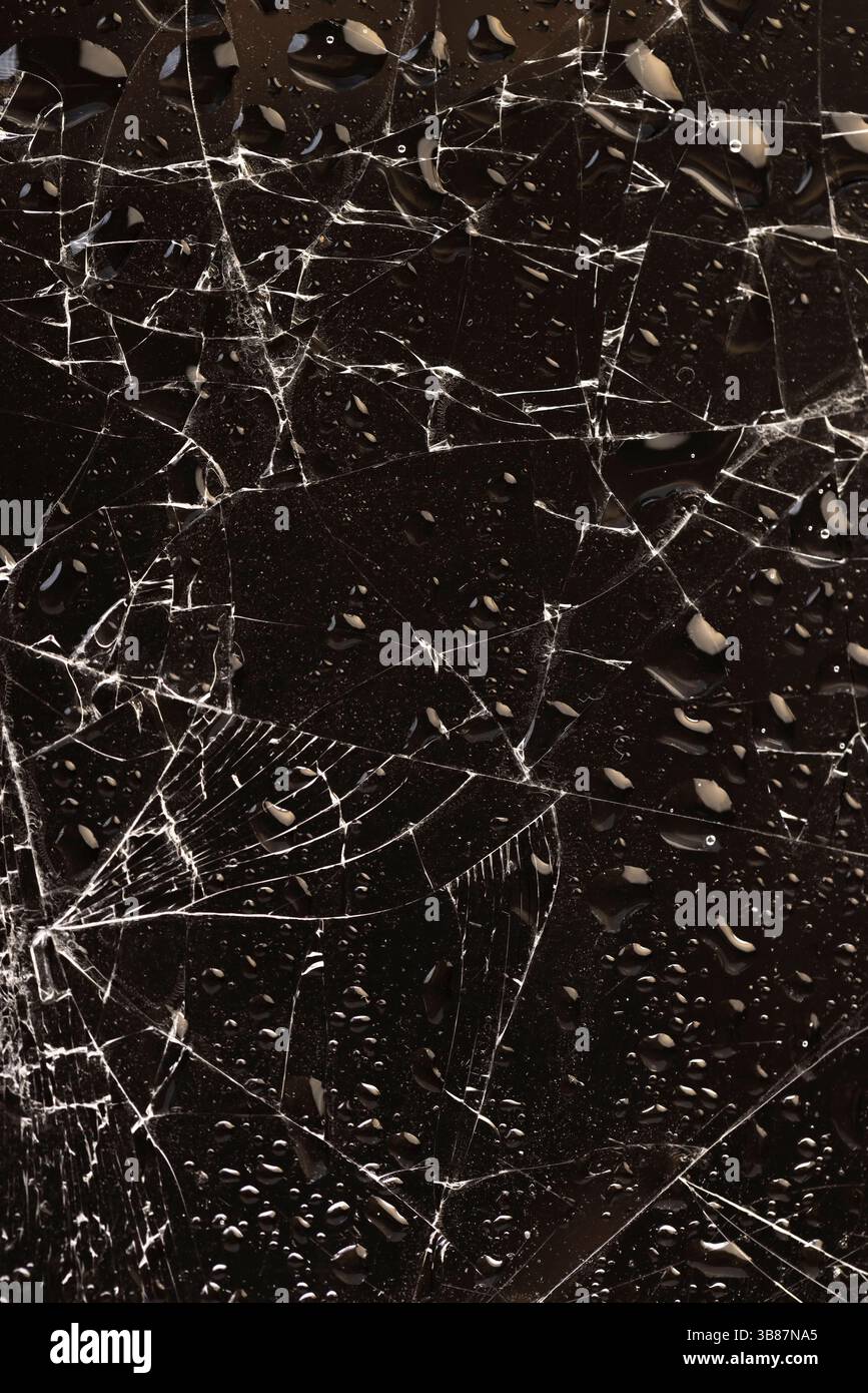 water covered broken glass with a lot of damage on a dark background ...