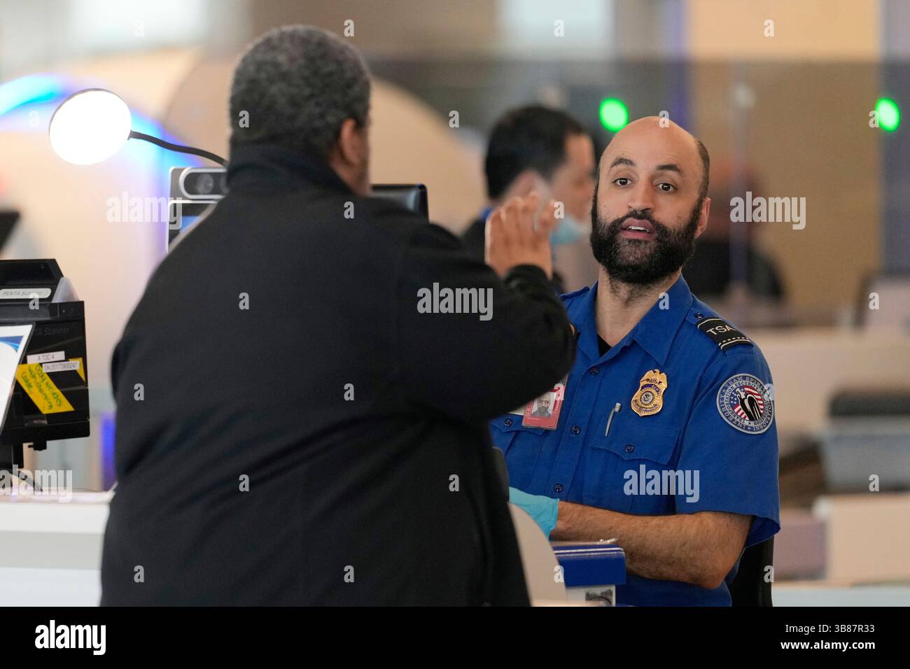 A TSA employee checks IDs as people move through security at Newark ...