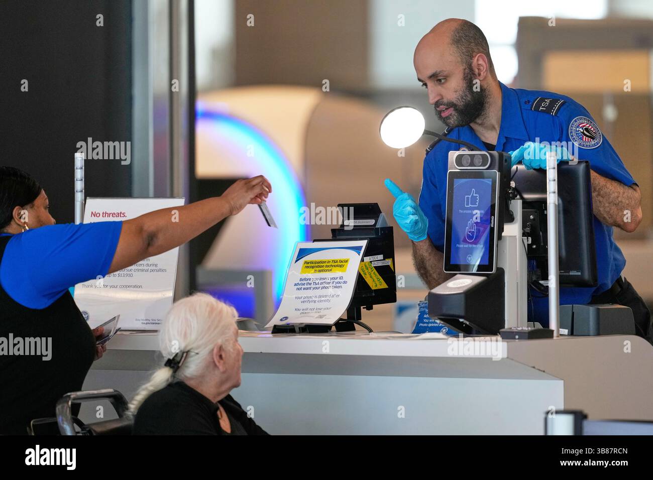A TSA employee checks IDs as people move through security at Newark ...