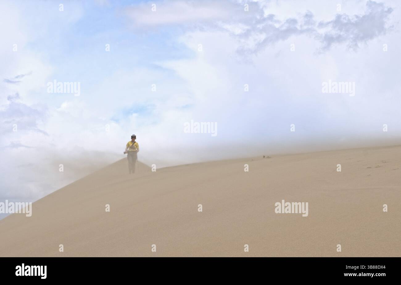 Tourist walking along the edge of the sand dune. Large barkhan in ...