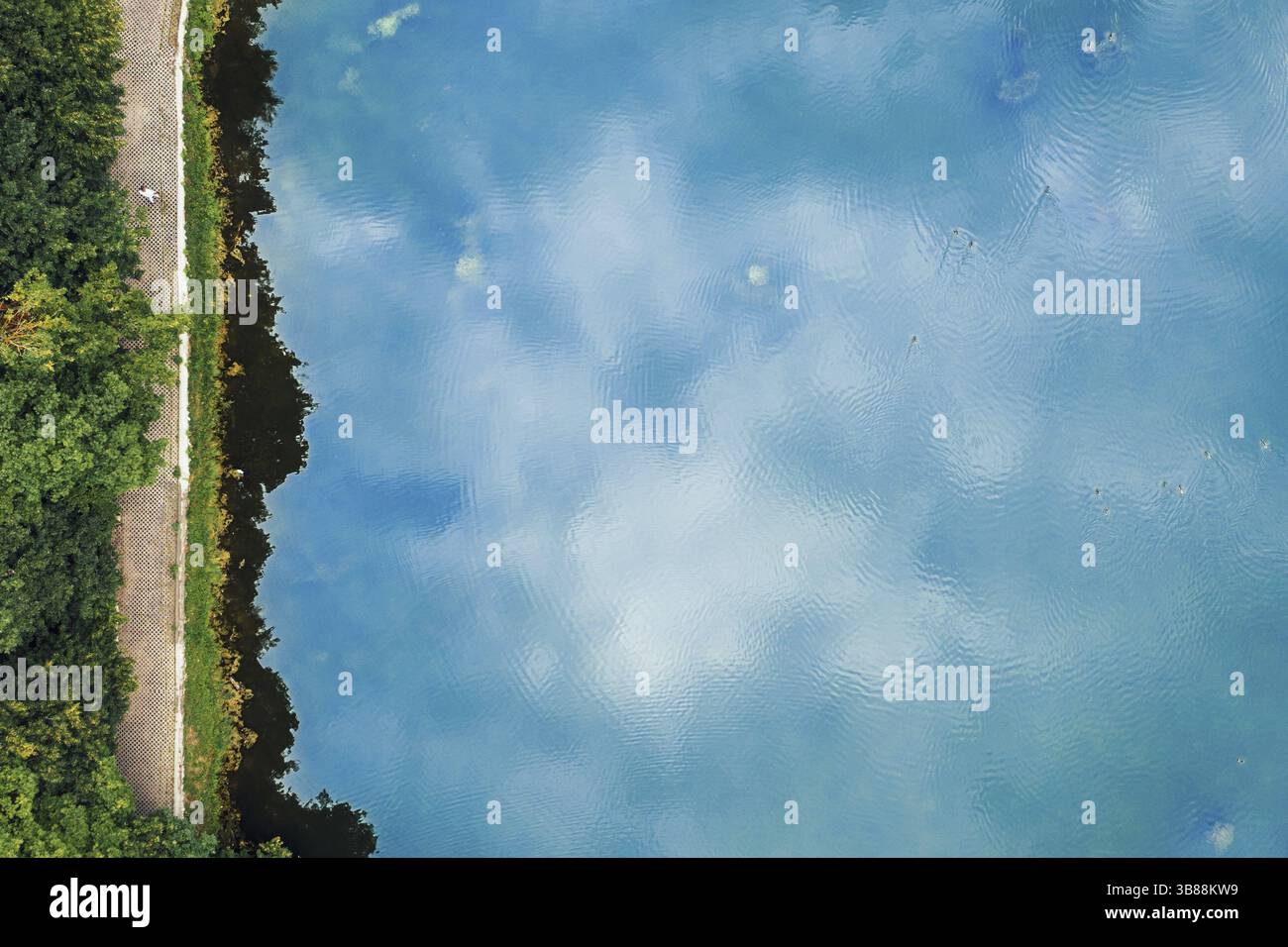 Blue water surface of lake with reflecting clouds, top view. Narrow ...