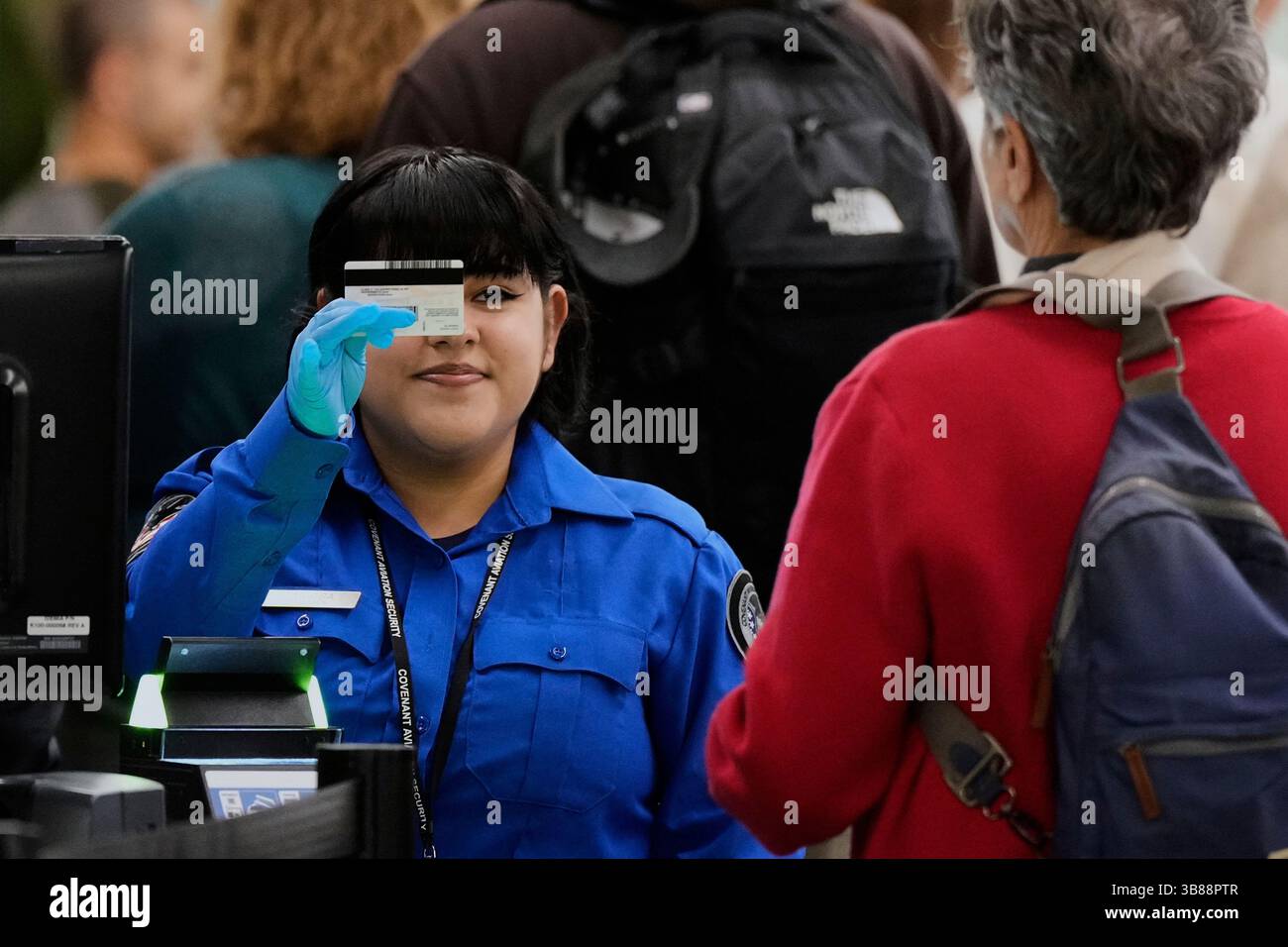 A TSA employee checks a traveler's ID at a security checkpoint in San ...
