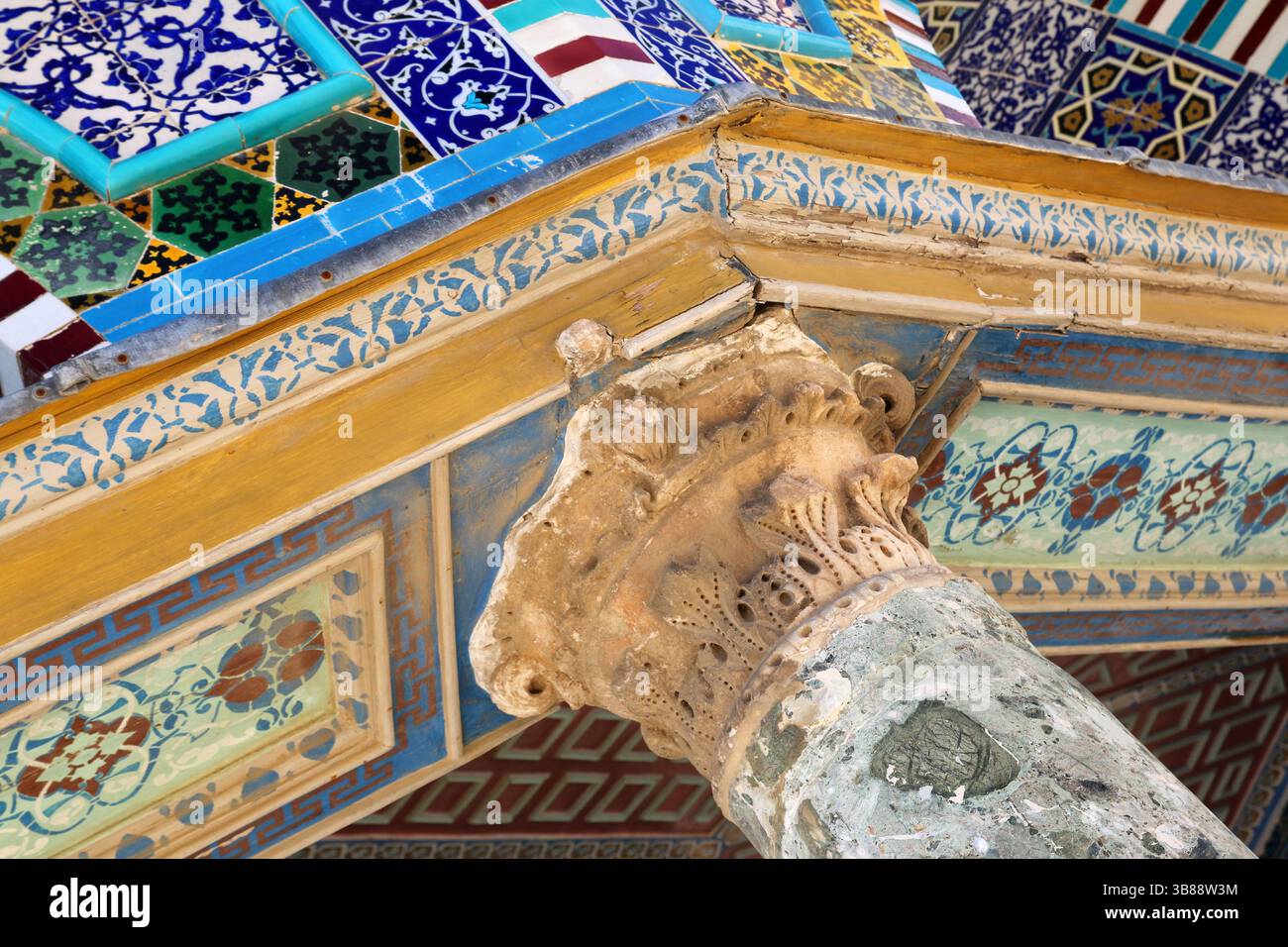 Close-up of ornate column capital and colorful Islamic tile mosaics ...