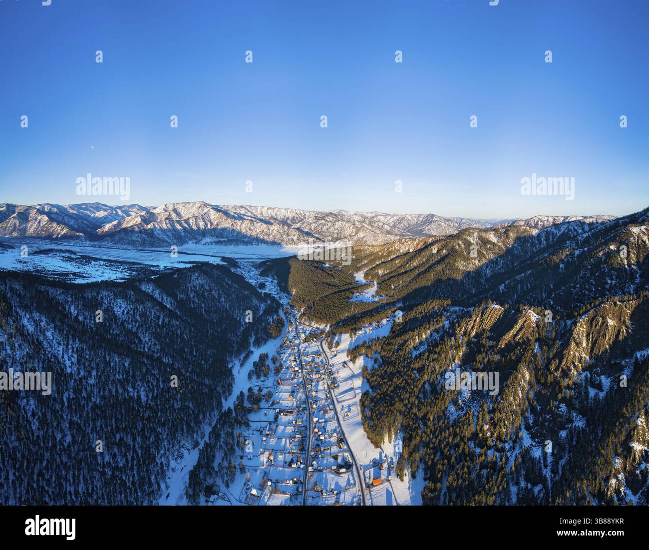 Winter village in the valley of the river between the mountains. Aerial ...
