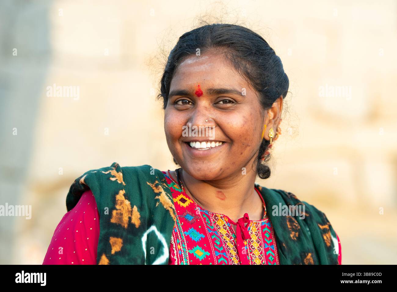 Portrait of an indian woman dressed in traditional colorful clothes, red bindi dot on her ...