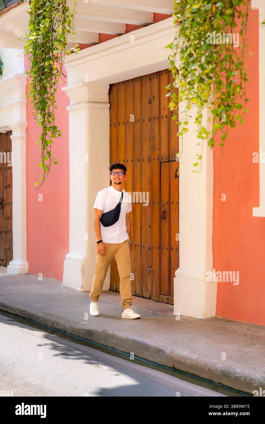 Young Latino man wearing white shirt and khaki pants stands relaxed and ...