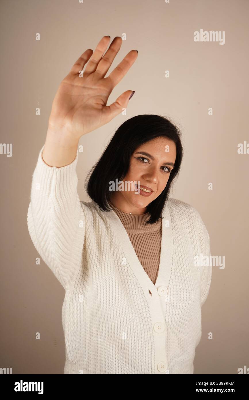 A single hand raised with an open palm delivers a clear "stop" signal ...