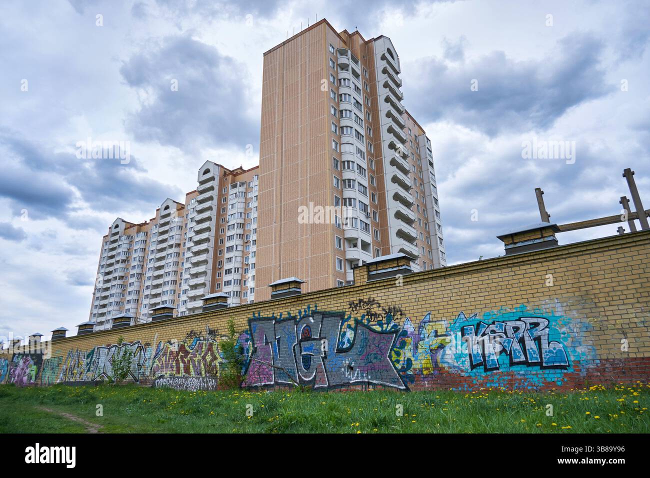Graffiti on a brick fence and a multi-story residential building ...