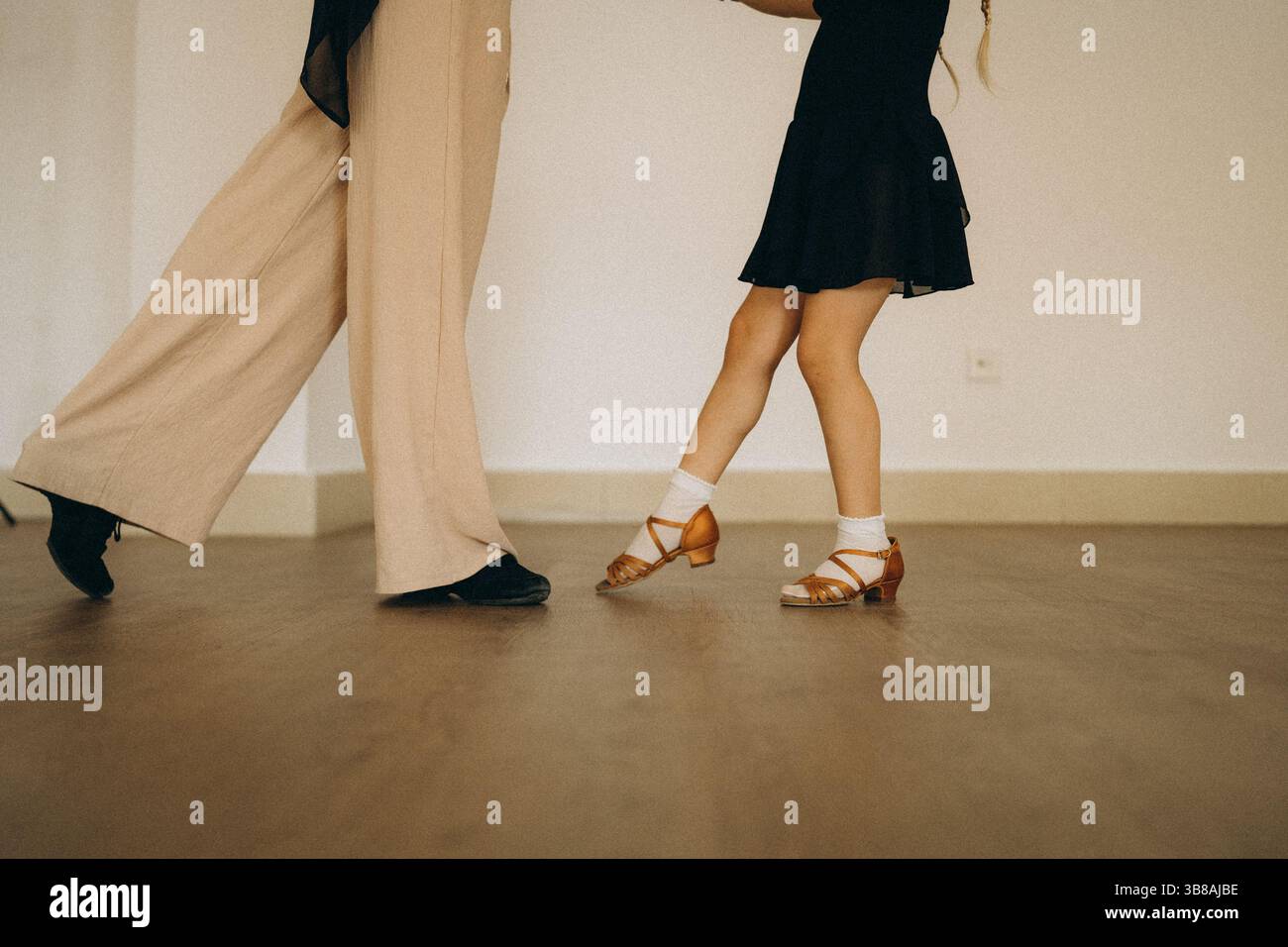 Adult and child dancing together in ballroom shoes. Close-up of legs on ...