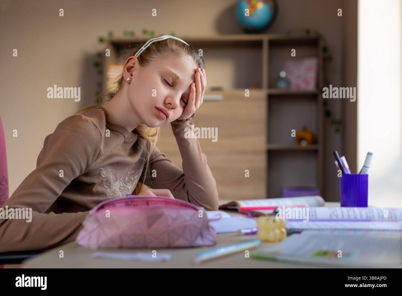 Tired schoolgirl resting head on hand at a desk Stock Photo - Alamy
