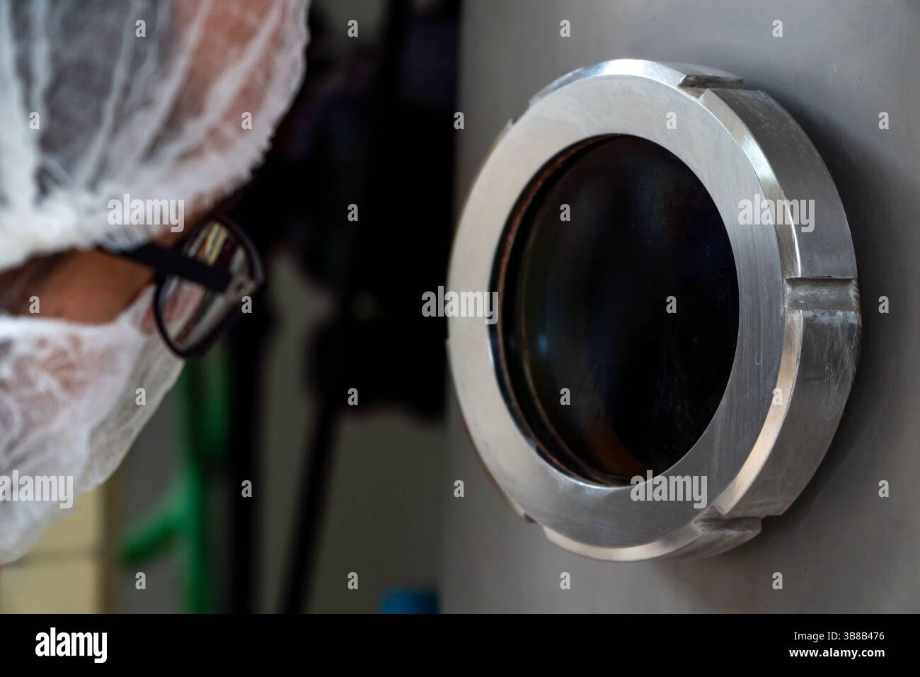 Control technician monitoring process through tank sight glass with net ...