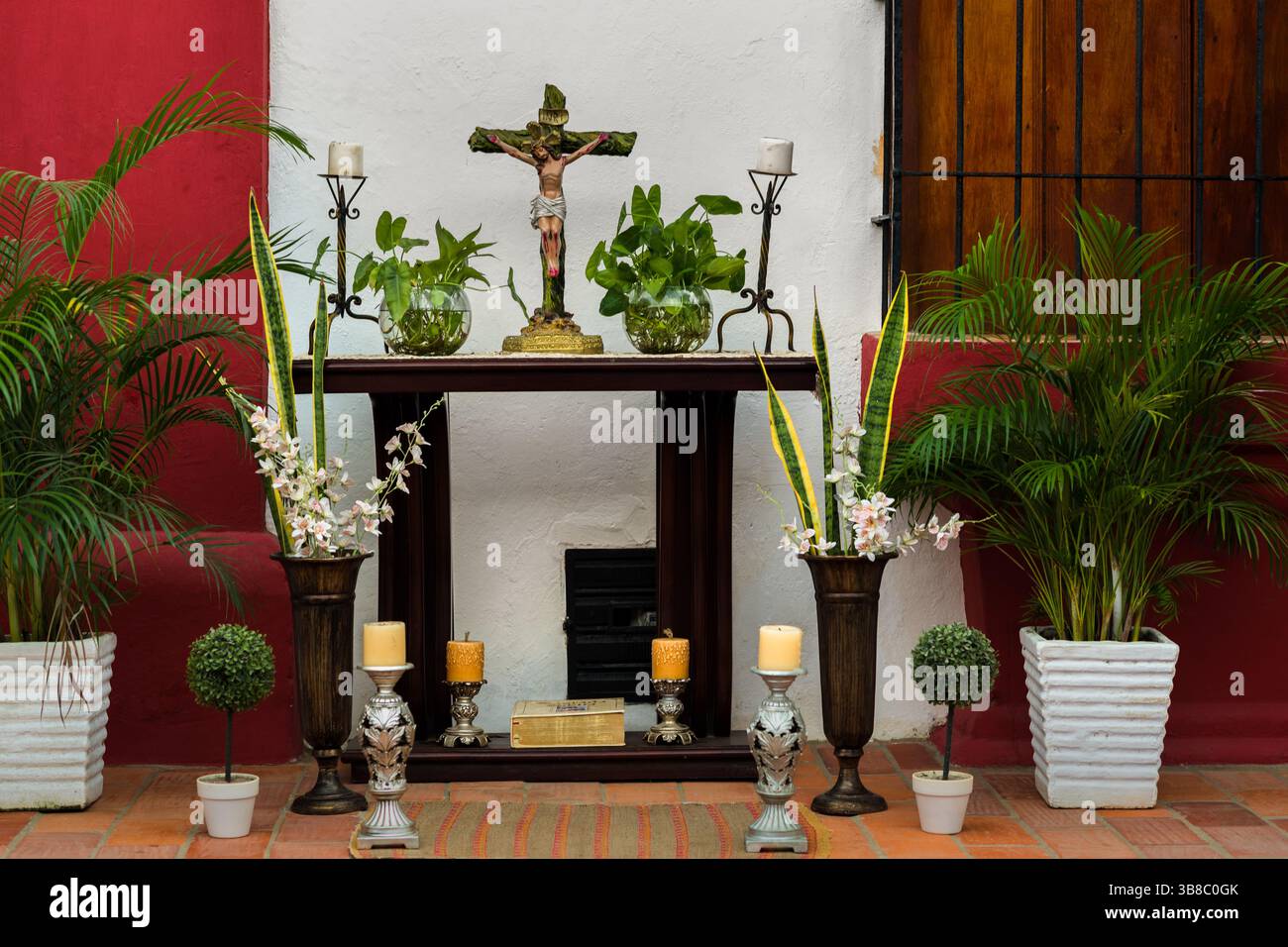 An ornate tabletop crucifix is seen placed beside plants and ...