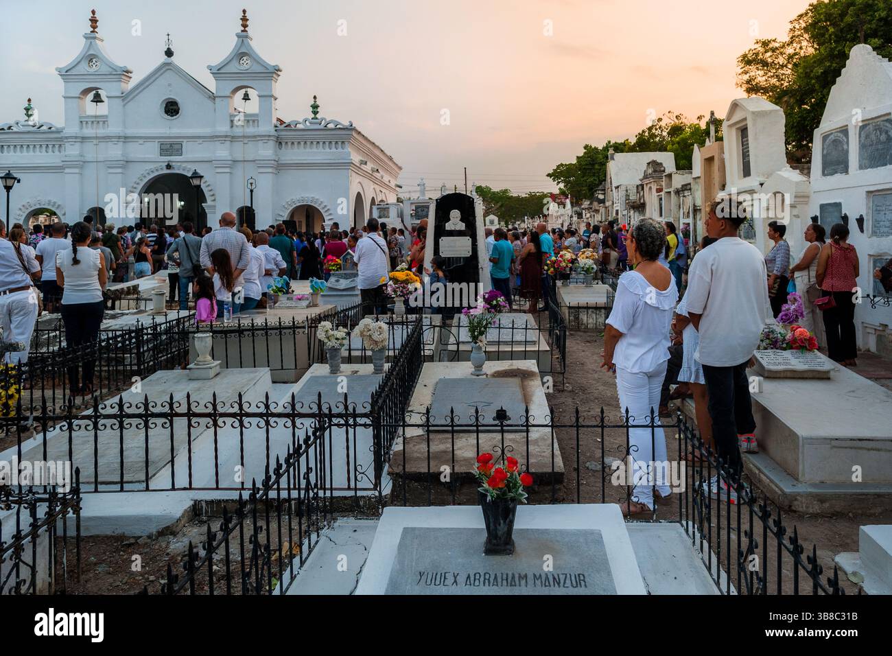 Colombians stand among tombs as they attend an evening mass during the ...