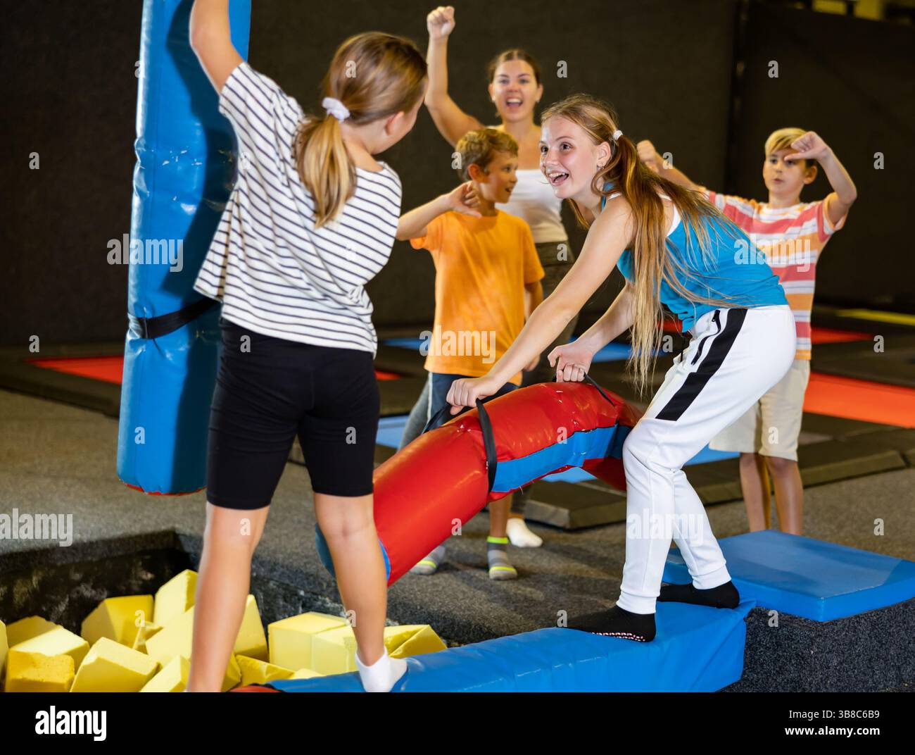 Teen girl doing funny fighting on battle beam with preteen girl Stock ...