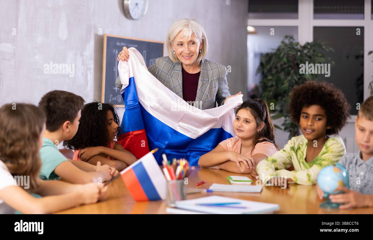 Female teacher Female teacher showing russian flag to kids in geography ...