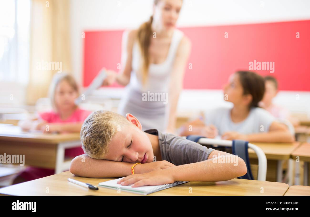 Tired school boy sleeping in classroom during lesson Stock Photo - Alamy