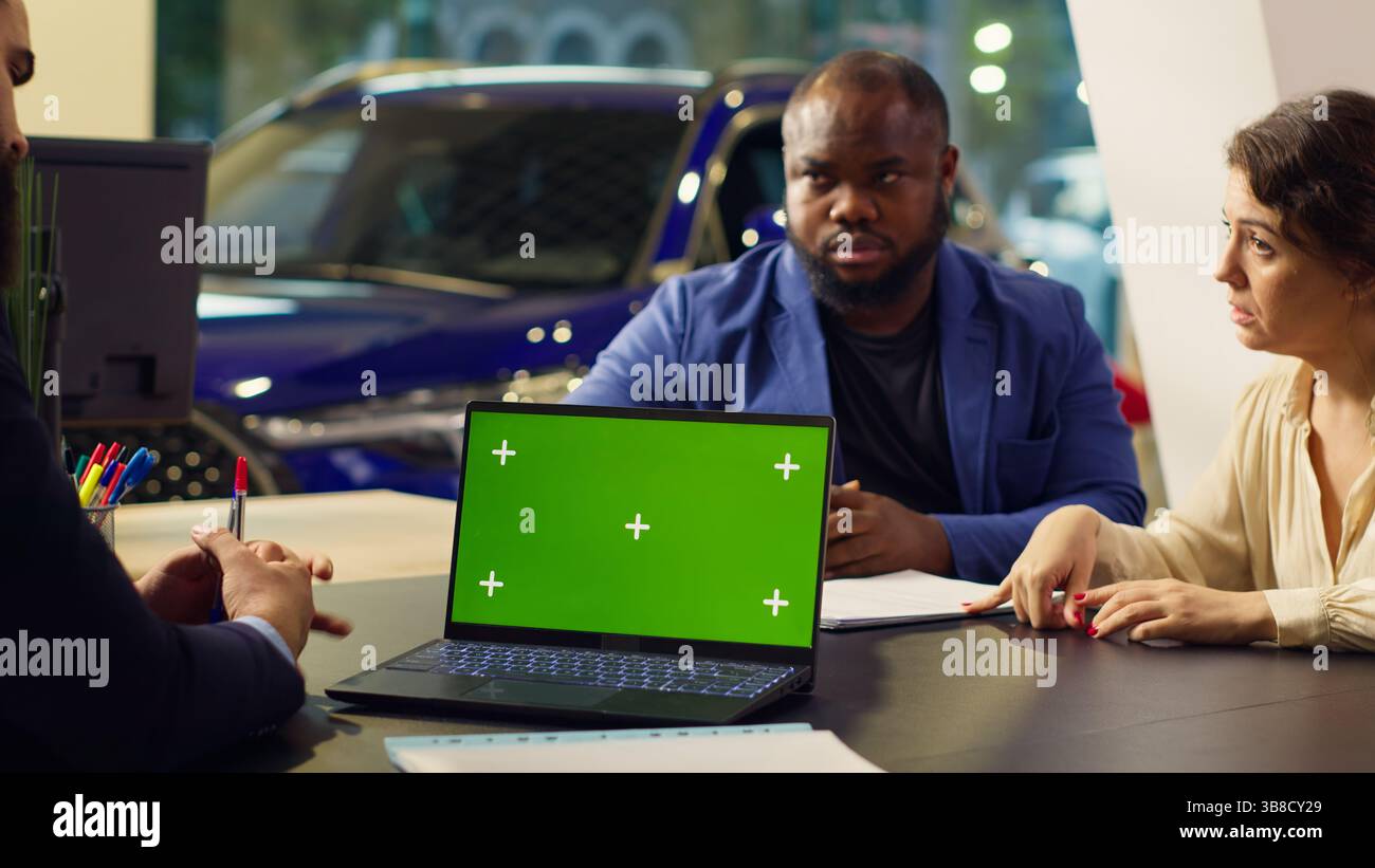 Dealership salesman looking over appointment list on chroma key laptop ...