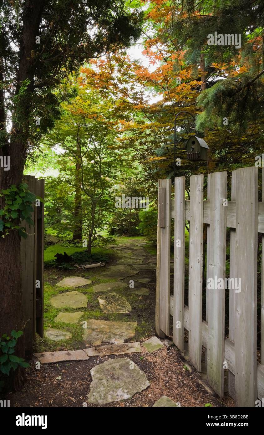 Opened wooden fence gate and flagstone path leading to backyard garden ...
