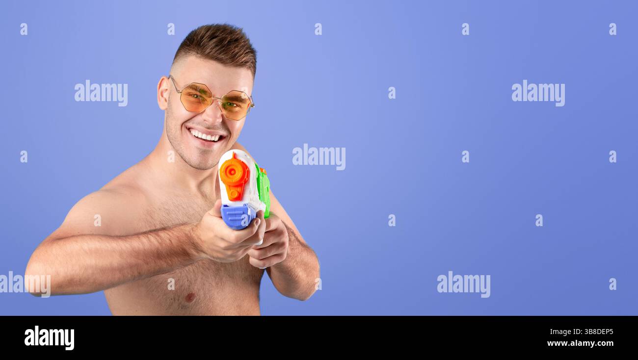 Summer vacation concept. Attractive millennial man pointing water gun ...