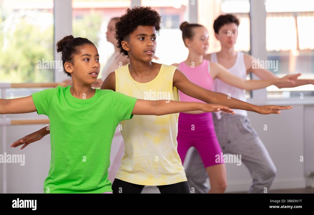 Teenage girl and boy practicing plie position of ballet in dance studio ...