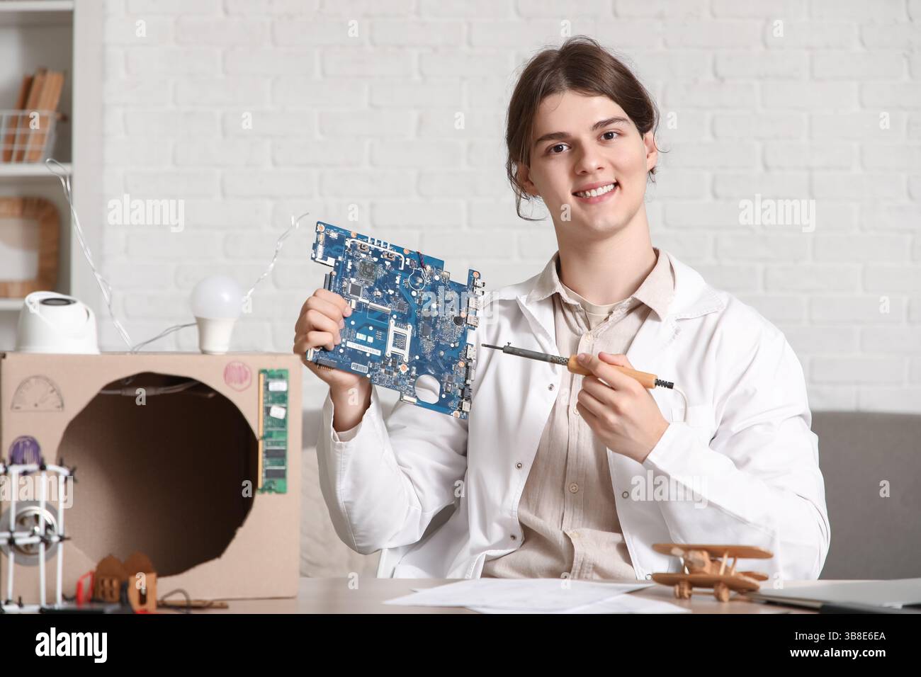 Male inventor with soldering iron and computer board in office Stock ...