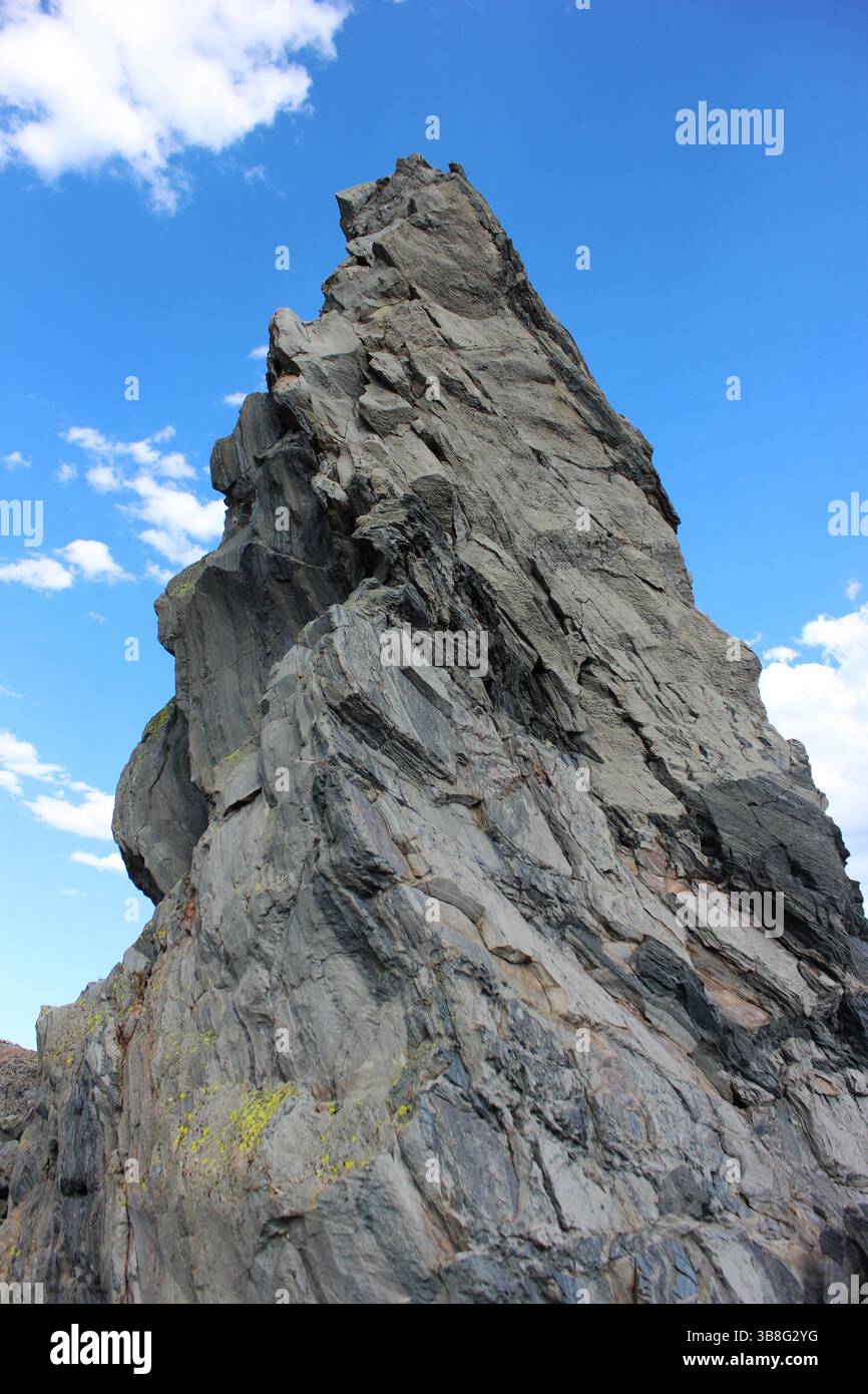 Massive rock formation stands prominently against a bright blue sky ...