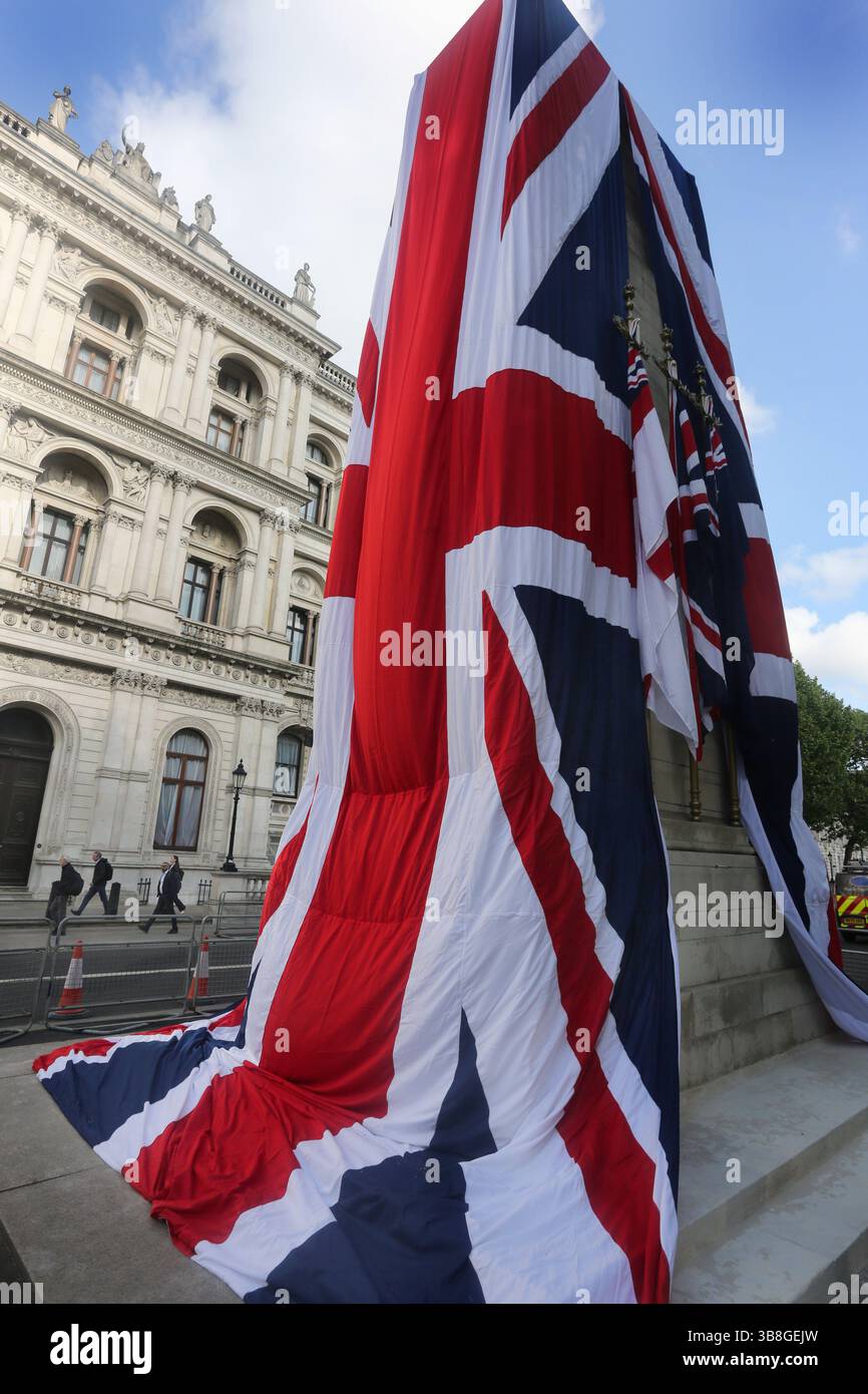 People in the distance pass by the large flag draping the cenotaph. The ...