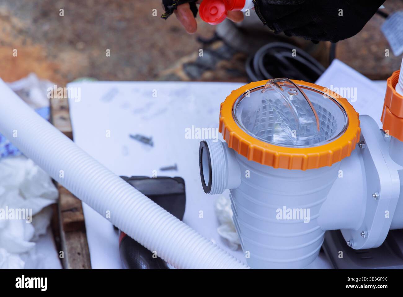 Worker prepares components of water swimming pool pump, handling parts at construction site ...