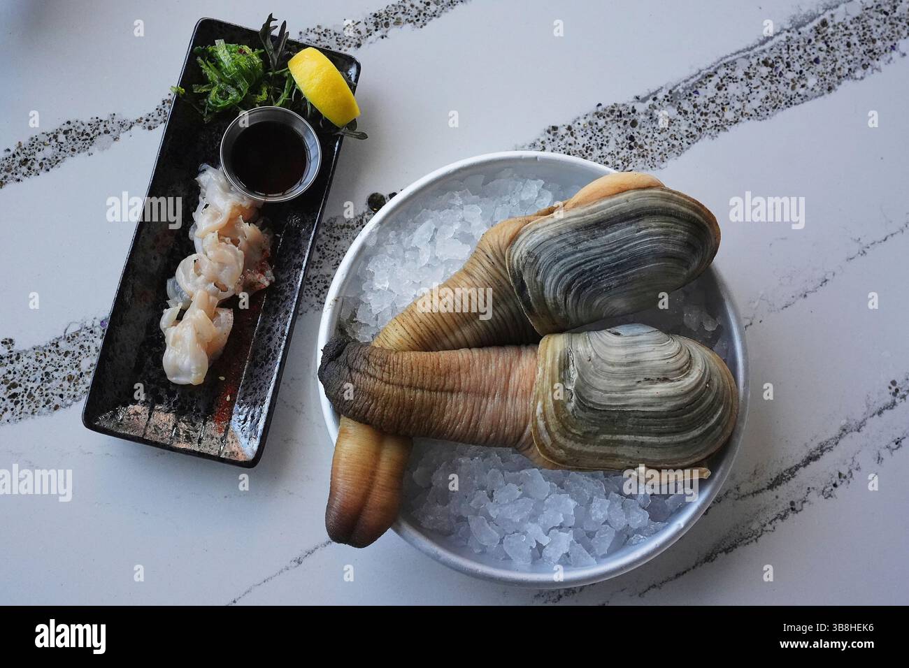 A sashimi preparation of geoducks at left contrasts with two whole ...