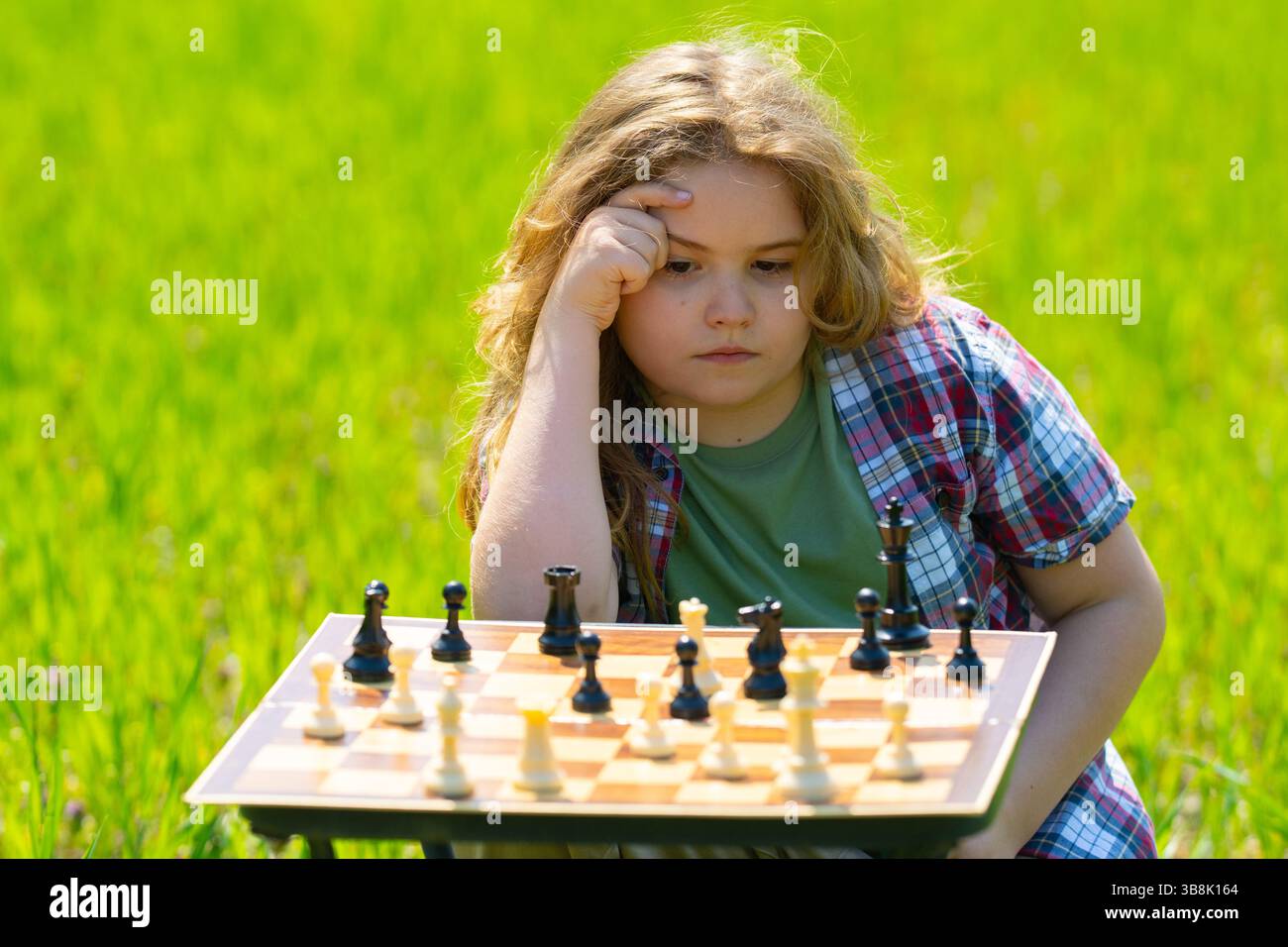 Kid plays chess. A child thinks and playing chess. Kid focuses on ...