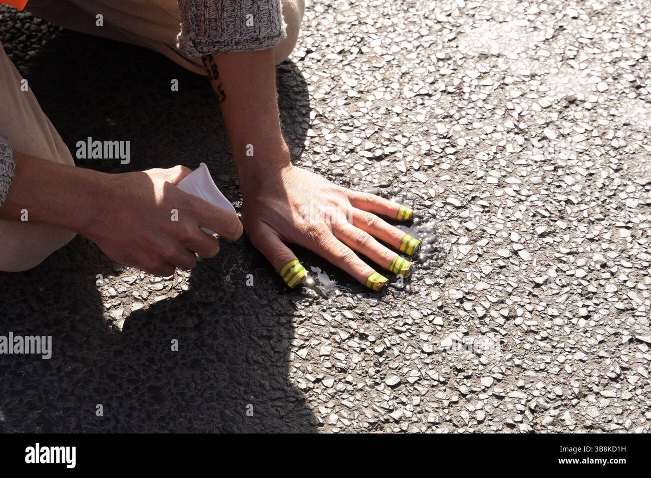 A climate activist glues and cements his hand to the road during the ...