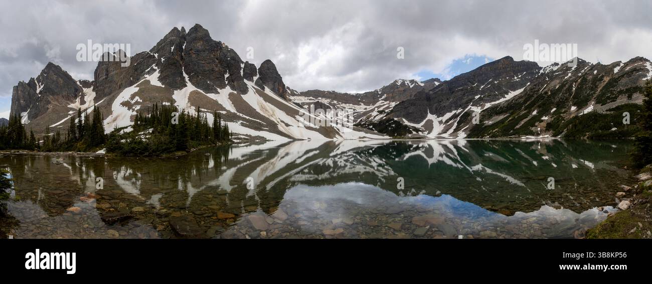 Majestic mountain peaks tower above a calm lake, their reflections ...