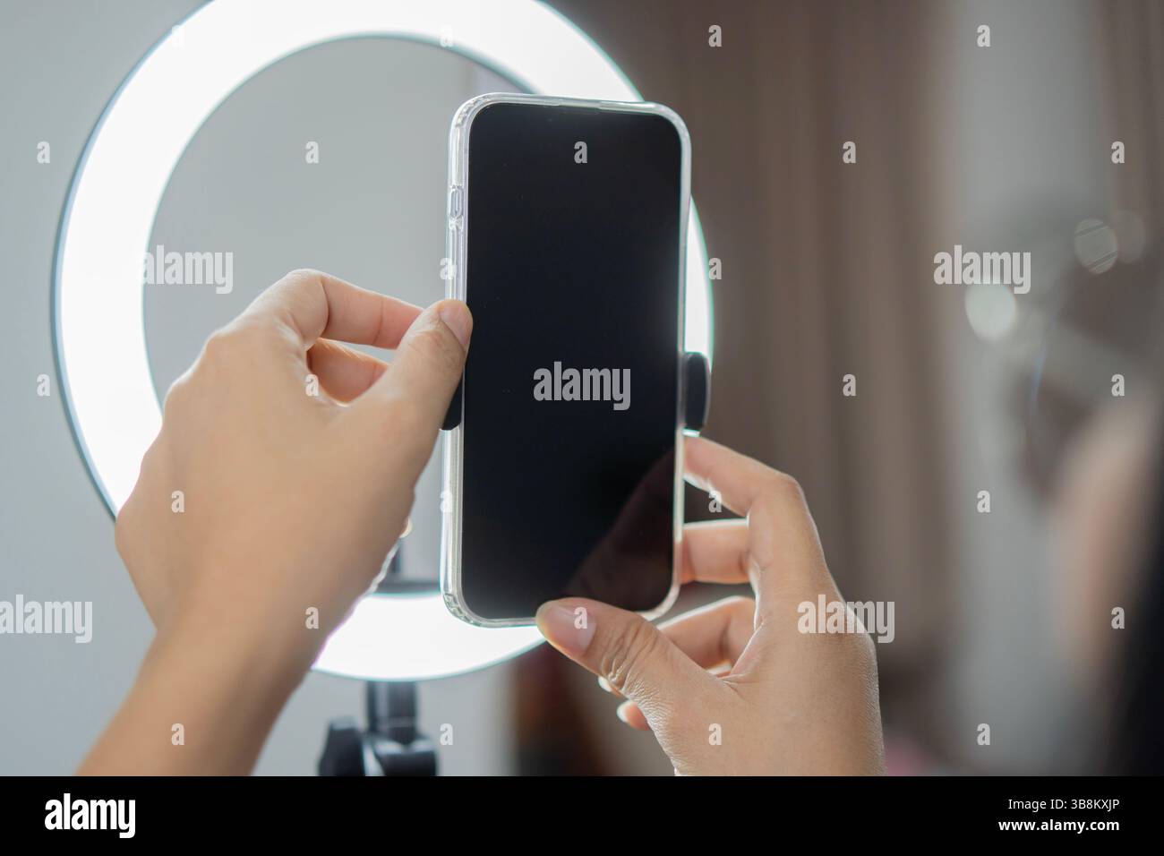 Hands of influencer adjusting smart phone on ring light at home ...